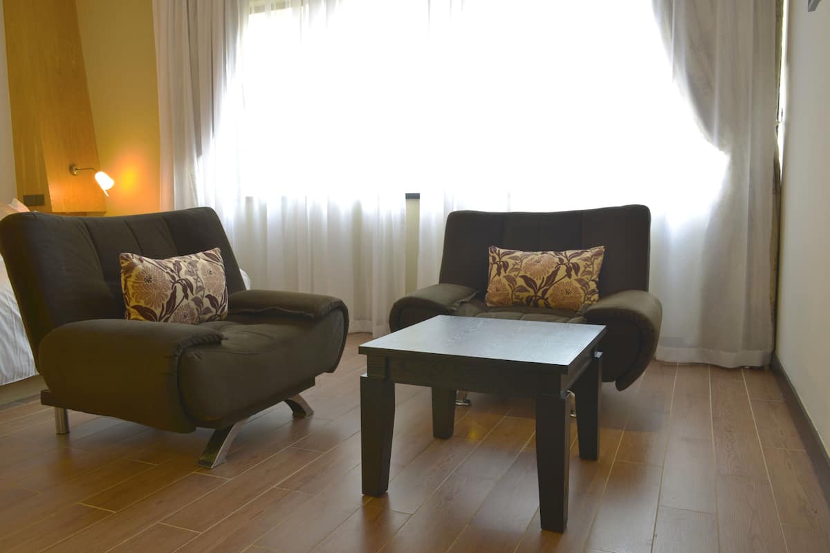 Uma sala de estar com dois sofás, uma mesa de centro e um abajur.