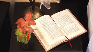 Um livro aberto sobre uma mesa preta, com uma pequena planta e um objeto decorativo ao fundo.