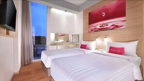 Quarto de hotel com duas camas, televisão, escrivaninha e uma janela grande.
