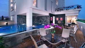 Um hotel moderno com piscina no terraço, área de estar externa e bar/lounge com vista para o horizonte da cidade.