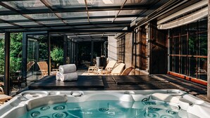 Uma área de spa com hidromassagem, cadeiras de descanso e um pátio envidraçado.