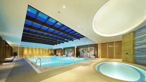 Piscina interna com claraboia, ofurô e área de estar rebaixada.