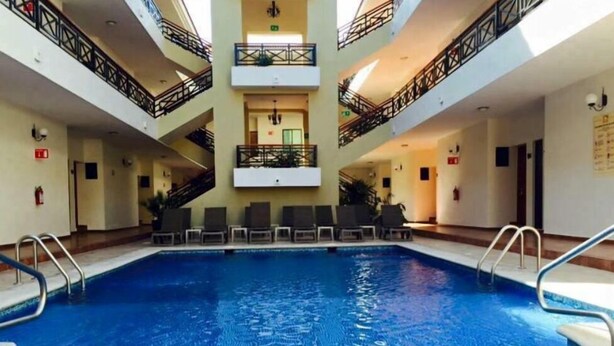 Piscina interior em vários níveis, com água cristalina, rodeada por espreguiçadeiras e corrimãos.