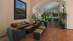 Um hall amplo com sofás, poltronas e plantas em vasos.