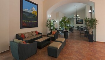 Um hall amplo com sofás, poltronas e plantas em vasos.