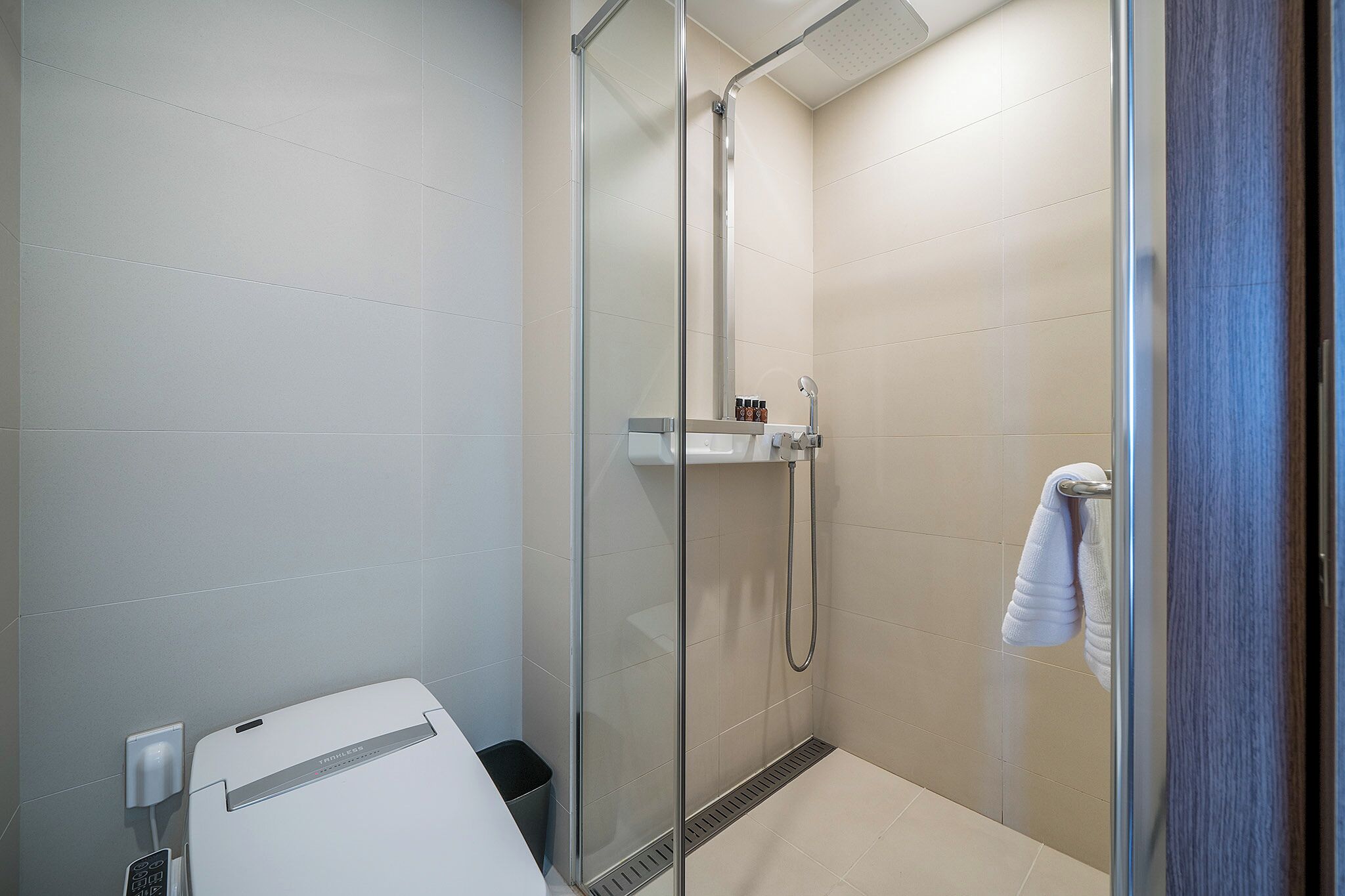 Casa de banho moderna com cabine de duche em vidro, lavatório branco e porta-toalhas.