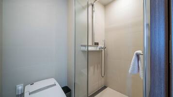 Casa de banho moderna com cabine de duche em vidro, lavatório branco e porta-toalhas.