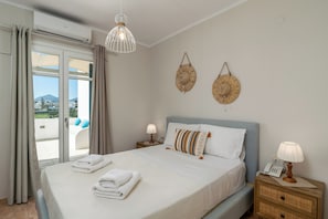 Quarto com cama, duas mesas de cabeceira, luminária na parede e vista pela janela.