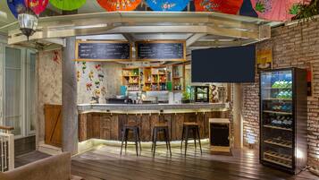 Uma área de bar com banquetas de madeira, um balcão com um quadro de menu e um climatizador de vinhos.