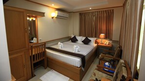 Quarto de hotel com cama, mesa de cabeceira, abajur e guarda-roupa.