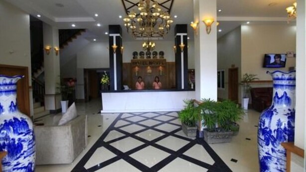Um saguão de hotel com uma mesa de recepção, um lustre e um piso estampado.