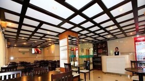 Restaurante com design moderno no teto, mesas e cadeiras de madeira e um refrigerador Coca-Cola.
