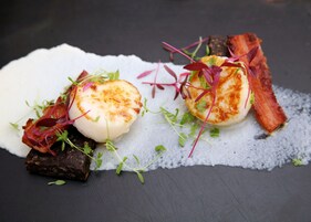 Prato com vieiras seladas, bacon e vegetais verdes.