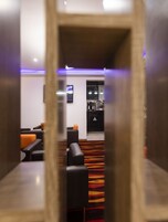 Um lobby moderno de hotel com balcão de recepção, área de estar e bar.