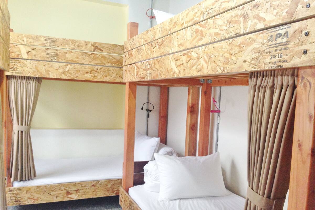 Quarto com beliches de madeira e roupa de cama branca.