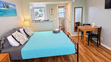 Quarto com cama, escrivaninha e vista para o exterior.