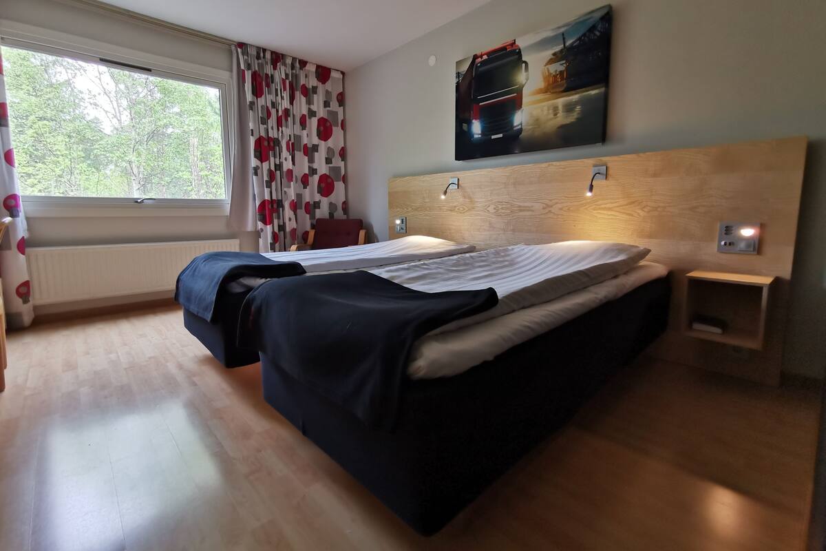 Quarto moderno com uma cama grande, mesas de cabeceira, uma janela com cortinas e um quadro na parede.