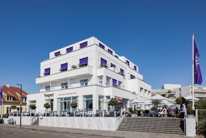 Um edifício branco com uma placa que diz "Vesper The Food & Cocktail Club" e área externa para sentar.