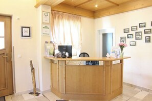 Uma mesa de recepção com certificados emoldurados na parede, uma mesa de madeira e uma janela com cortinas.