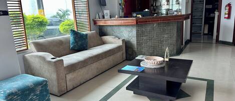 Um lobby moderno com um sofá, uma mesa de centro e um balcão de recepção.
