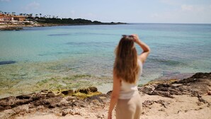 Uma paisagem costeira com águas turquesa cristalinas e uma linha de costa rochosa.