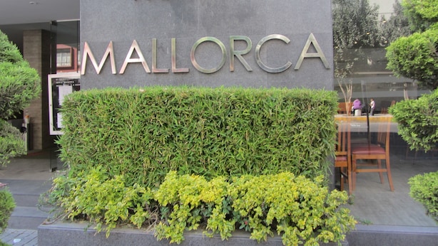 Placa de hotel com o nome 'HOTEL MALLORCA' e uma sebe bem cuidada à frente.
