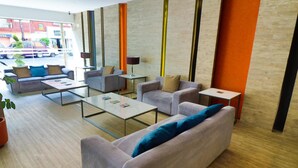Um hall de hotel moderno com área de estar, mesa de centro e abajur.