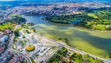 Vista aérea de uma cidade com um grande lago, uma praça central com uma cúpula amarela marcante e áreas verdes ao redor.