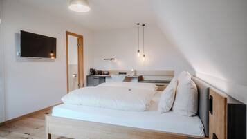 Quarto moderno com cama de madeira, uma escrivaninha, uma cadeira e uma TV fixada na parede.