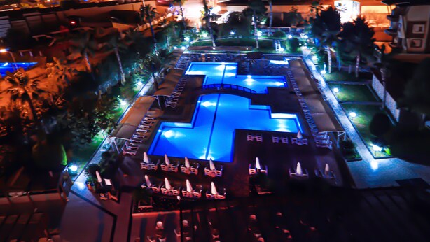 Um hotel com área de piscina, várias varandas e espaço ao ar livre bem iluminado.
