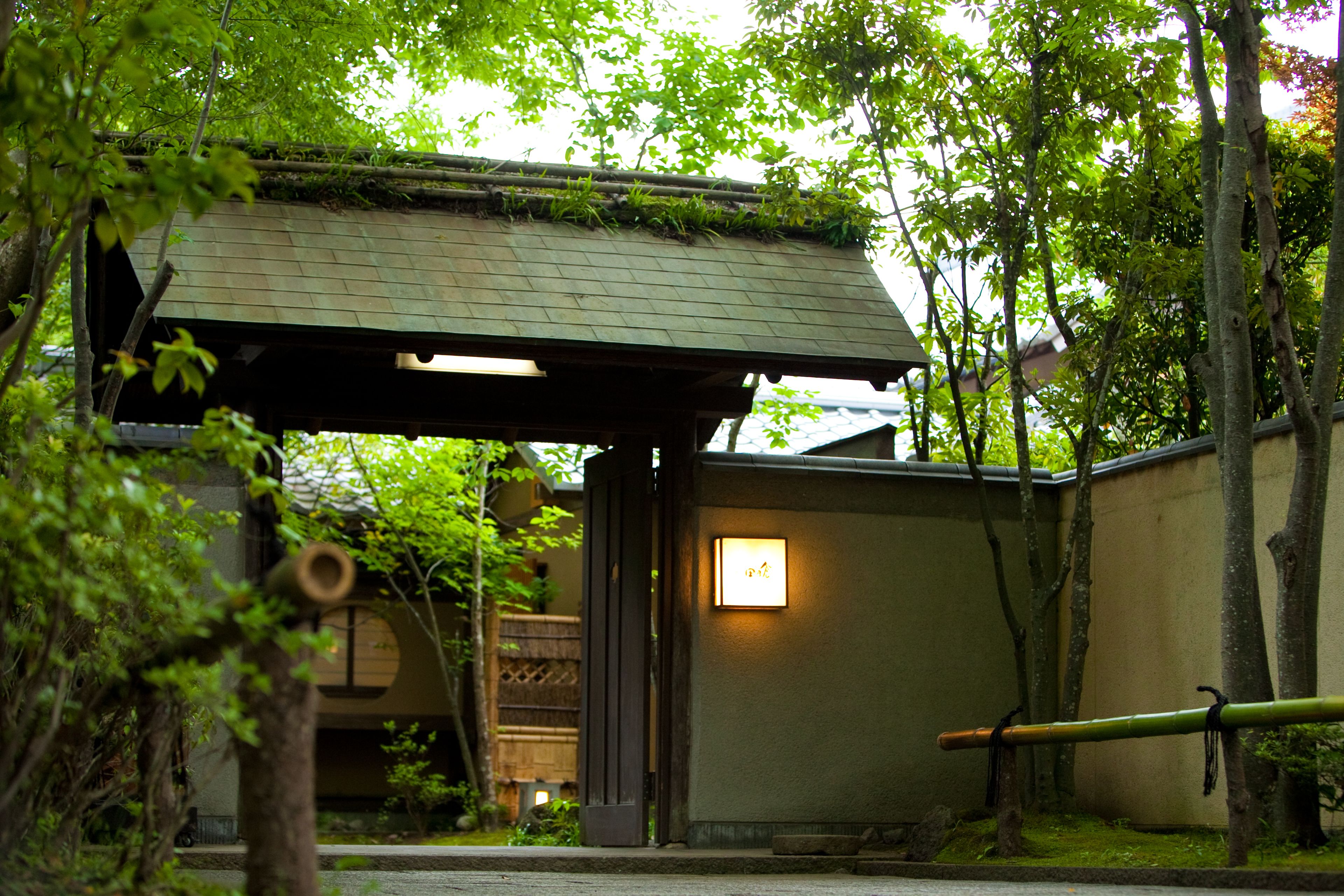 Um edifício japonês tradicional com telhado de telhas, um candeeiro e um banco de madeira.