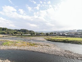 Um rio com margem rochosa e uma ponte ao longe.