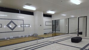Piscina interior moderna com linhas marcantes, área de estar acolchoada em preto e piso revestido de azulejos.