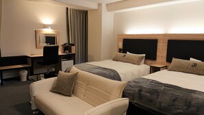 Quarto de hotel com duas camas, uma escrivaninha, uma cadeira, um sofá e um espelho.
