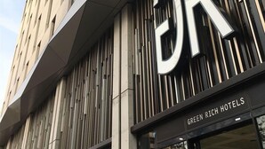 Um edifício com um letreiro grande com a letra 'DR' e o texto 'GREEN RICH HOTELS', indicando que se trata de um hotel.