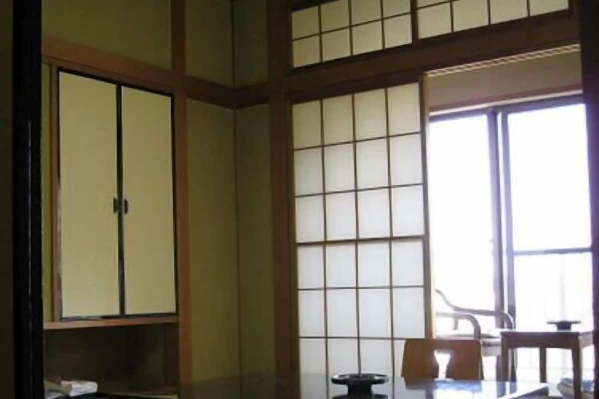 Um quarto japonês tradicional com tatames, uma mesa baixa e portas deslizantes.