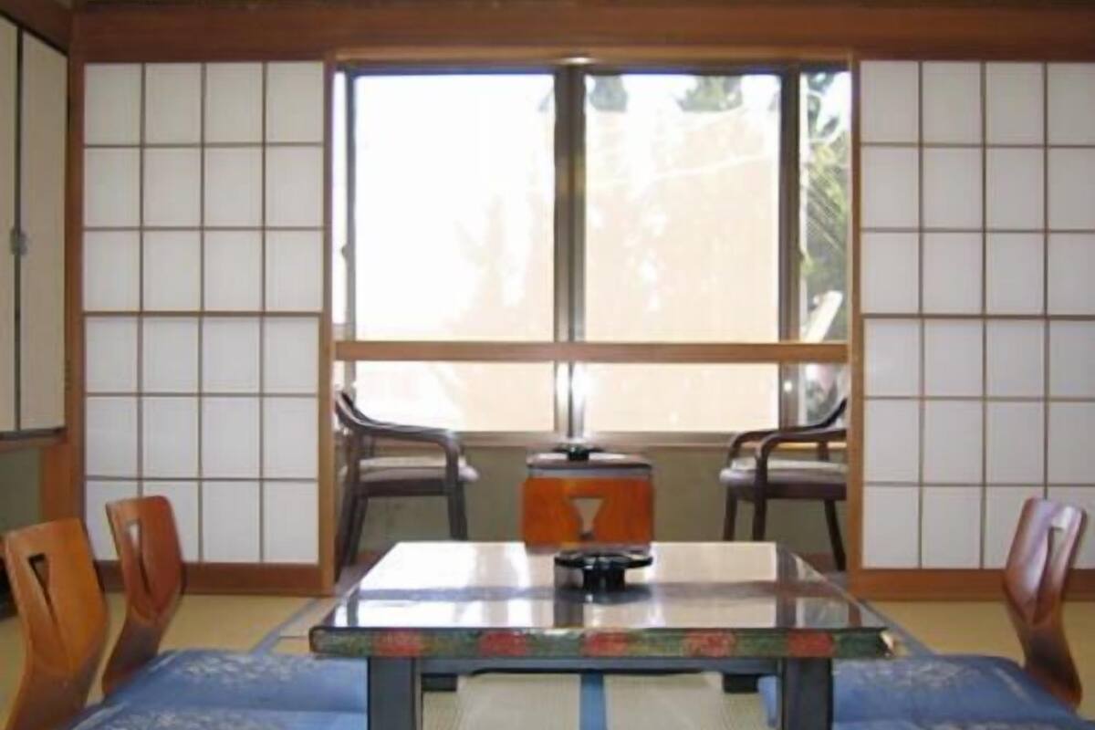 Um quarto japonês tradicional com tatames, uma mesa baixa e portas deslizantes.