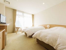 Quarto de hotel com duas camas, uma escrivaninha com um computador e uma cadeira.