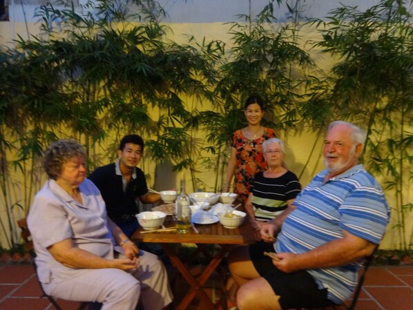 Um grupo de pessoas sentado à volta de uma mesa, com tigelas e pauzinhos, indicando um ambiente de refeição.