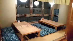 Um quarto japonês tradicional com assentos em esteiras de tatame e uma mesa de madeira baixa.