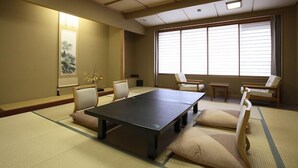Um quarto tradicional com tatame, uma mesa baixa e cadeiras, janelas amplas com persianas e um quadro na parede.