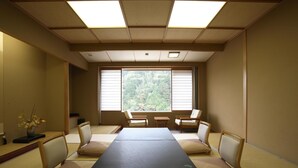 Sala de conferência com uma mesa comprida, quatro cadeiras e vista para uma floresta através de grandes janelas.