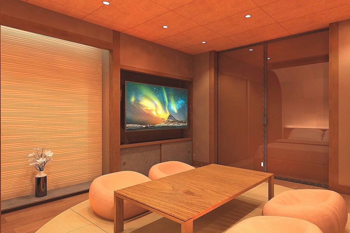 Quarto moderno com mesa de madeira, assentos acolchoados, televisão e porta de correr.