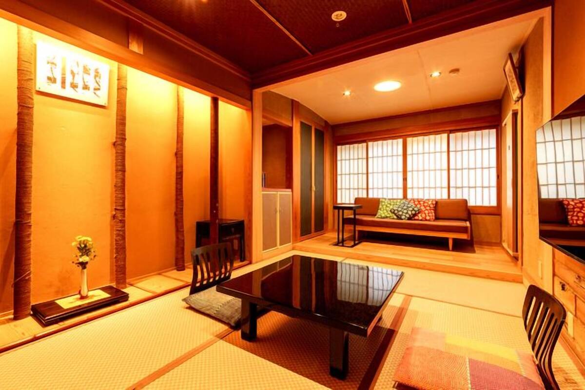 Um quarto japonês tradicional com tatames, uma mesa baixa e um sofá com almofadas.