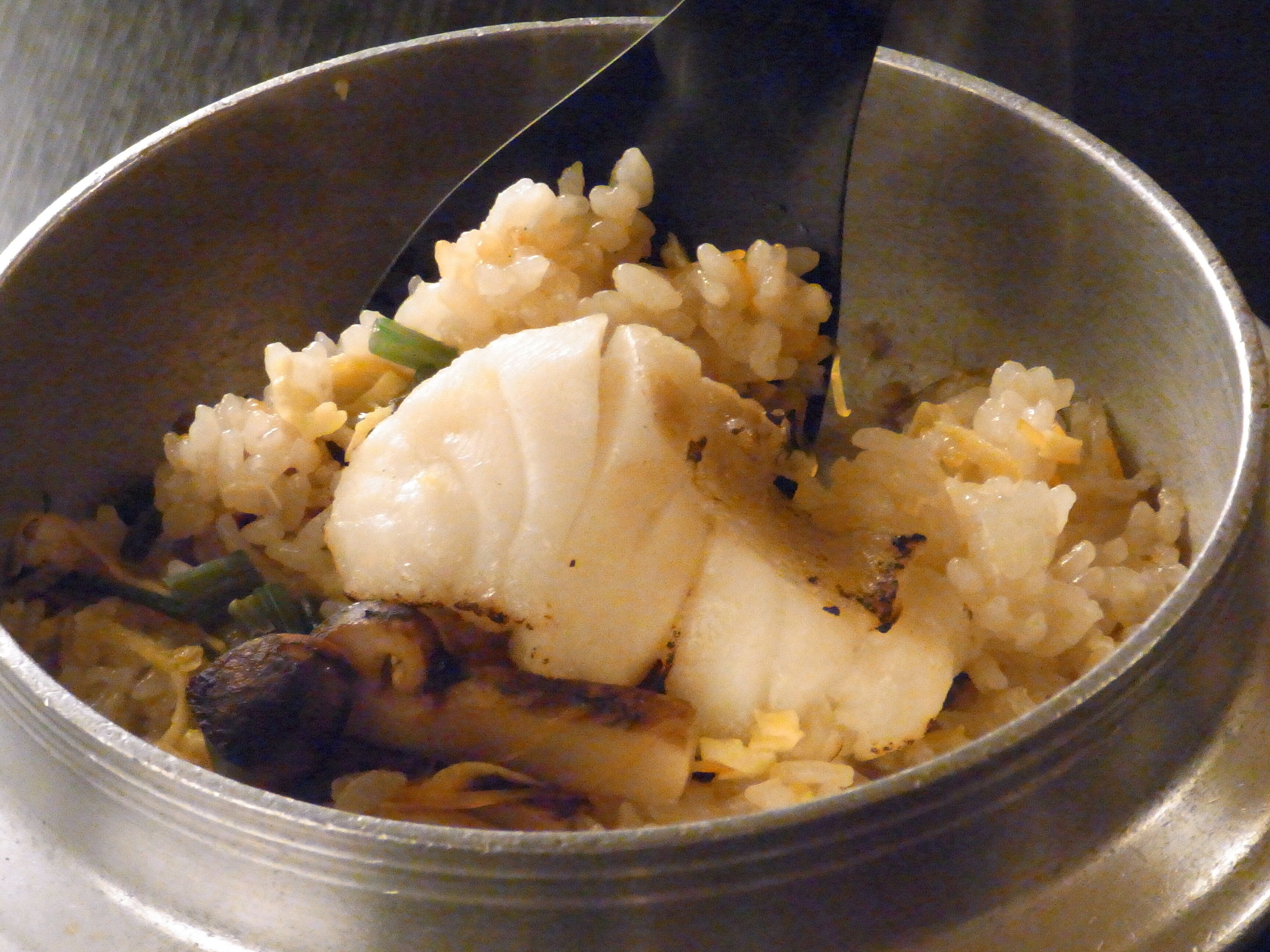 Uma tigela de arroz com um pedaço de peixe e cogumelos.