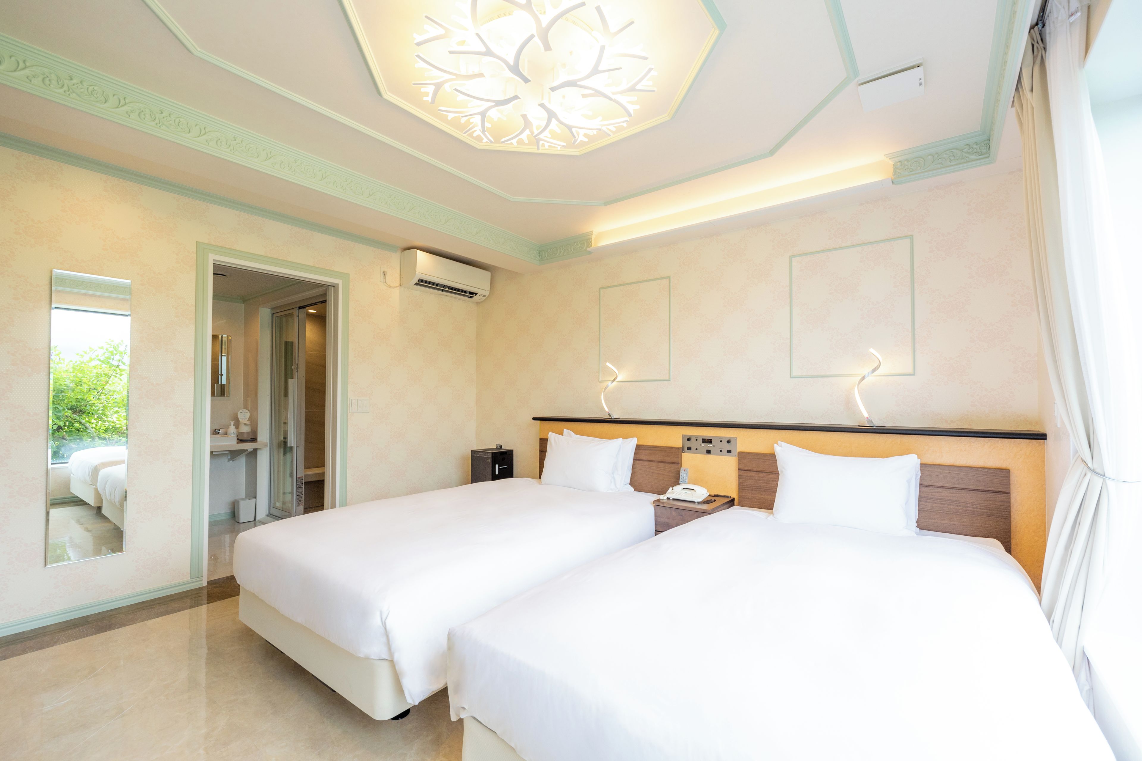 Quarto de hotel com duas camas, banheiro e um espelho grande.