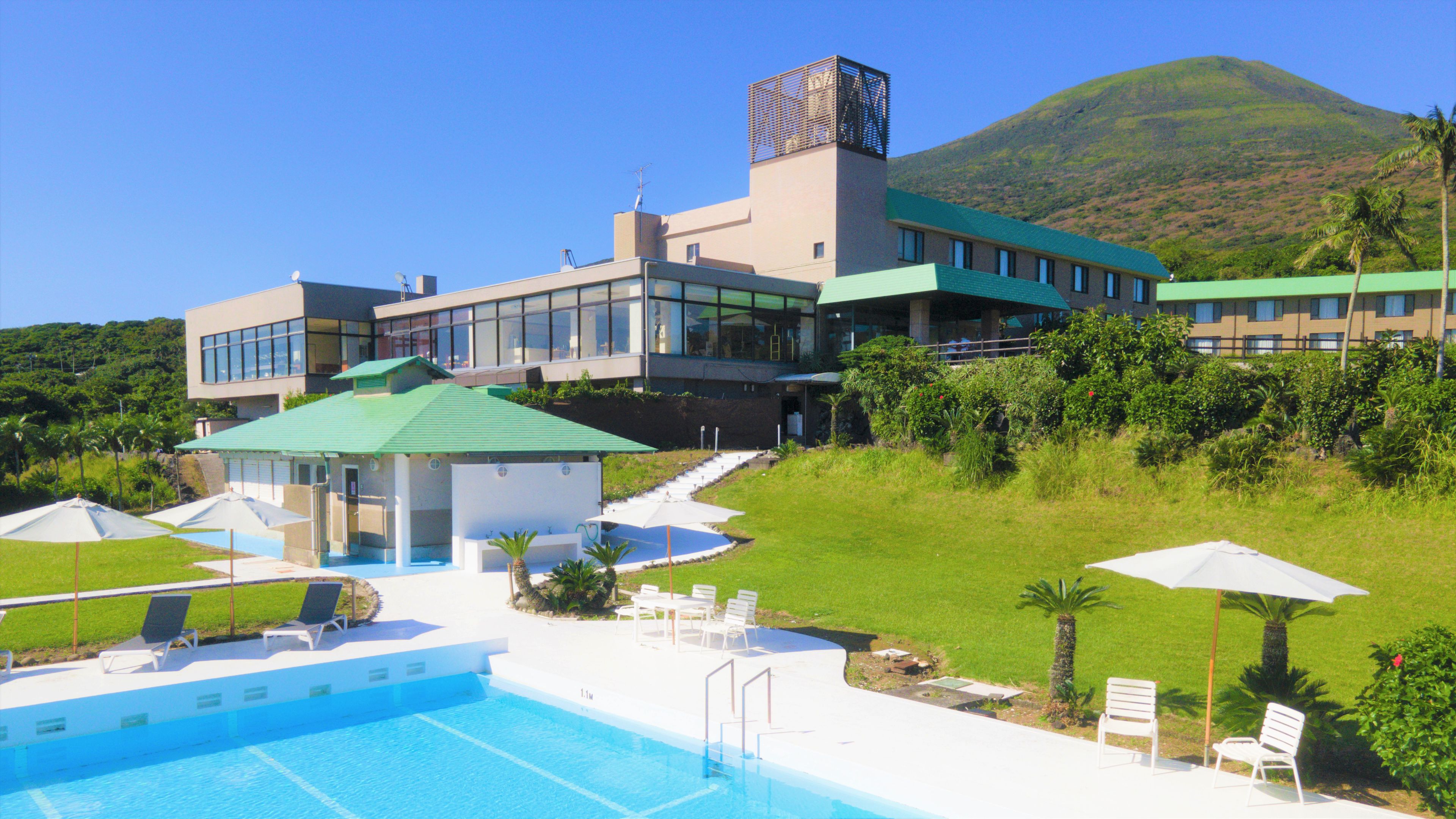 Hotel moderno com piscina, área de estar externa e vista para uma montanha.