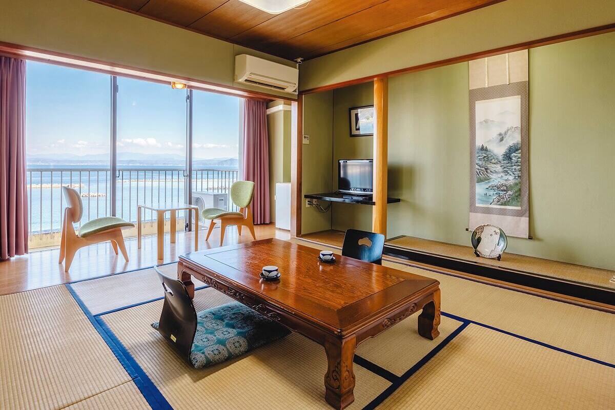 Um quarto em estilo japonês tradicional com tatames, uma mesa de madeira e cadeiras.