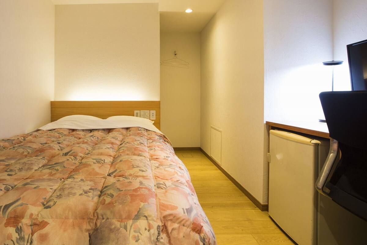 Um quarto com uma cama, uma escrivaninha e uma cadeira.