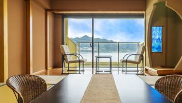 Uma sala de conferência com uma mesa grande e duas cadeiras, vista para um lago e montanhas através de grandes portas de vidro, e um design de interiores moderno.